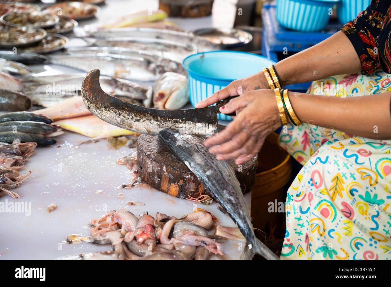 Indian woman cutting fish on a market in Mumbai India, sales stall with ...