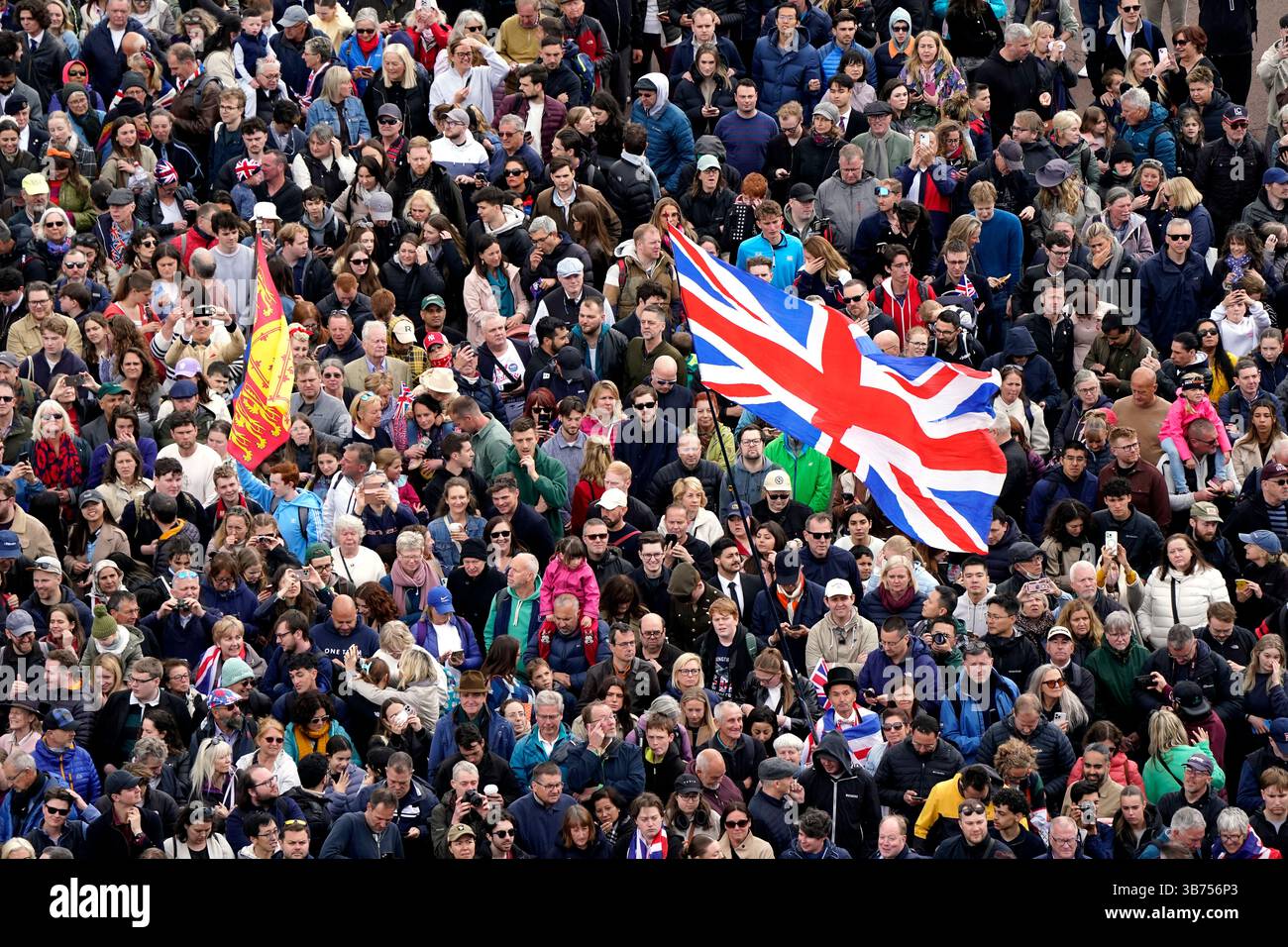 A person in the crowd waves a Union Jack flag, as members of the public ...