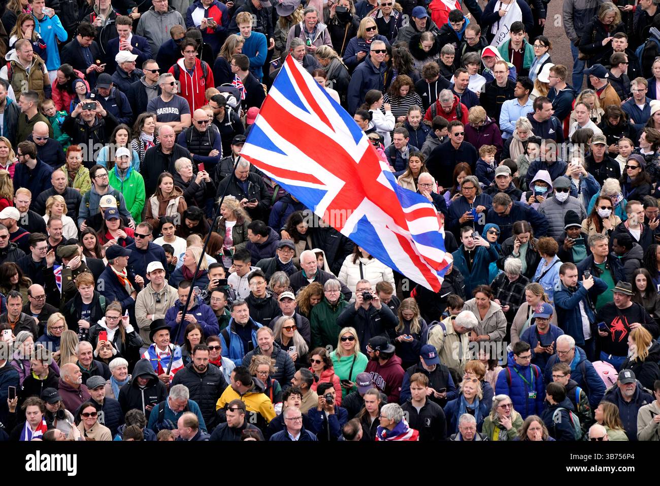 A person in the crowd waves a Union Jack flag, as members of the public ...