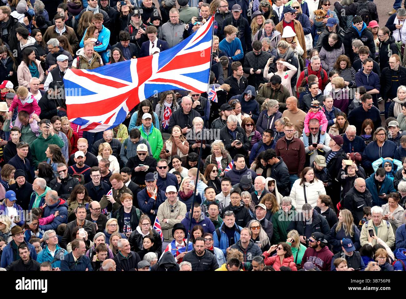 A person in the crowd waves a Union Jack flag, as members of the public ...