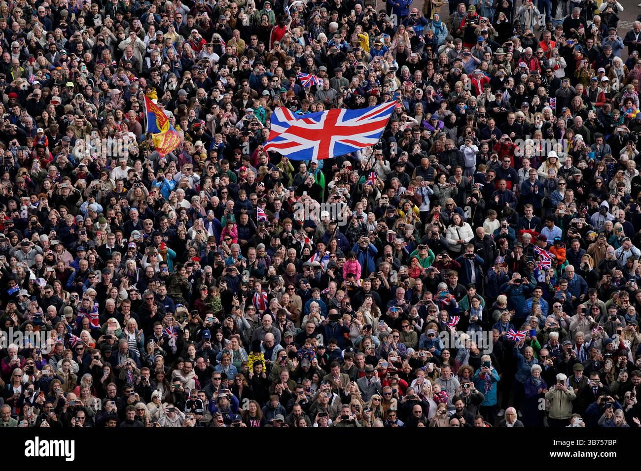 A person in the crowd waves a Union Jack flag, as members of the public ...