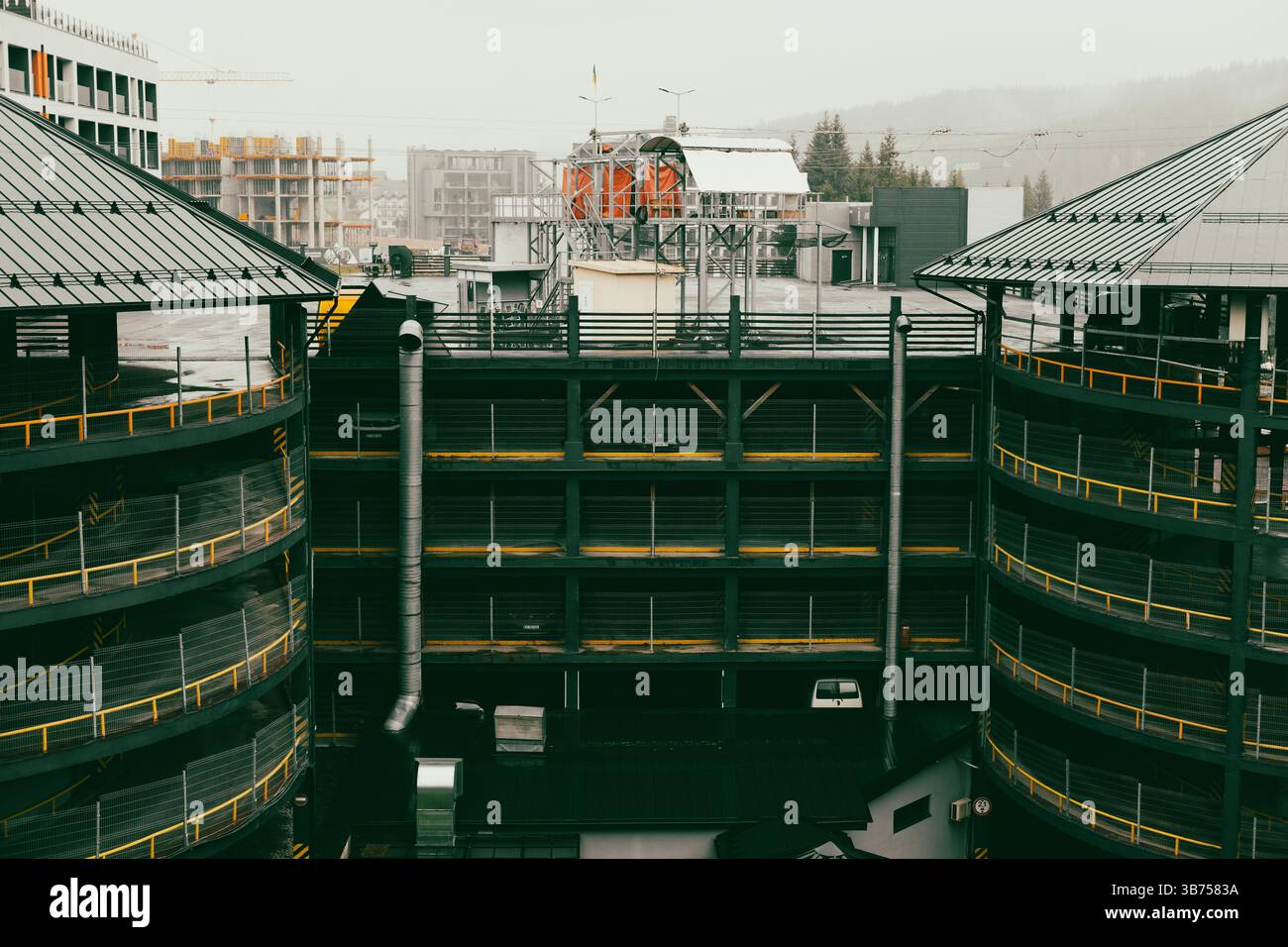 An urban scene with a multi-level parking garage and industrial structures amidst a foggy day ...