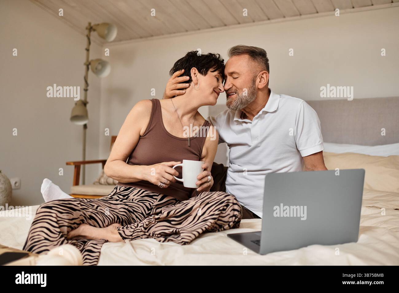 A happy couple enjoys a tender moment at home, sipping drinks and ...