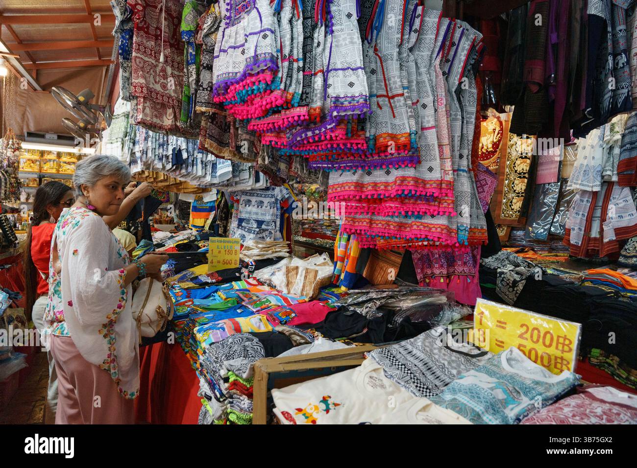 Bangkok, Thailand. 5th May, 2025. A tourist is choosing souvenir shirts at a store inside Wat ...