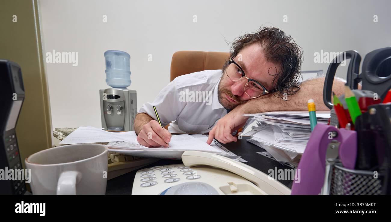 Exhausted office worker with glasses rests his head on stack of ...