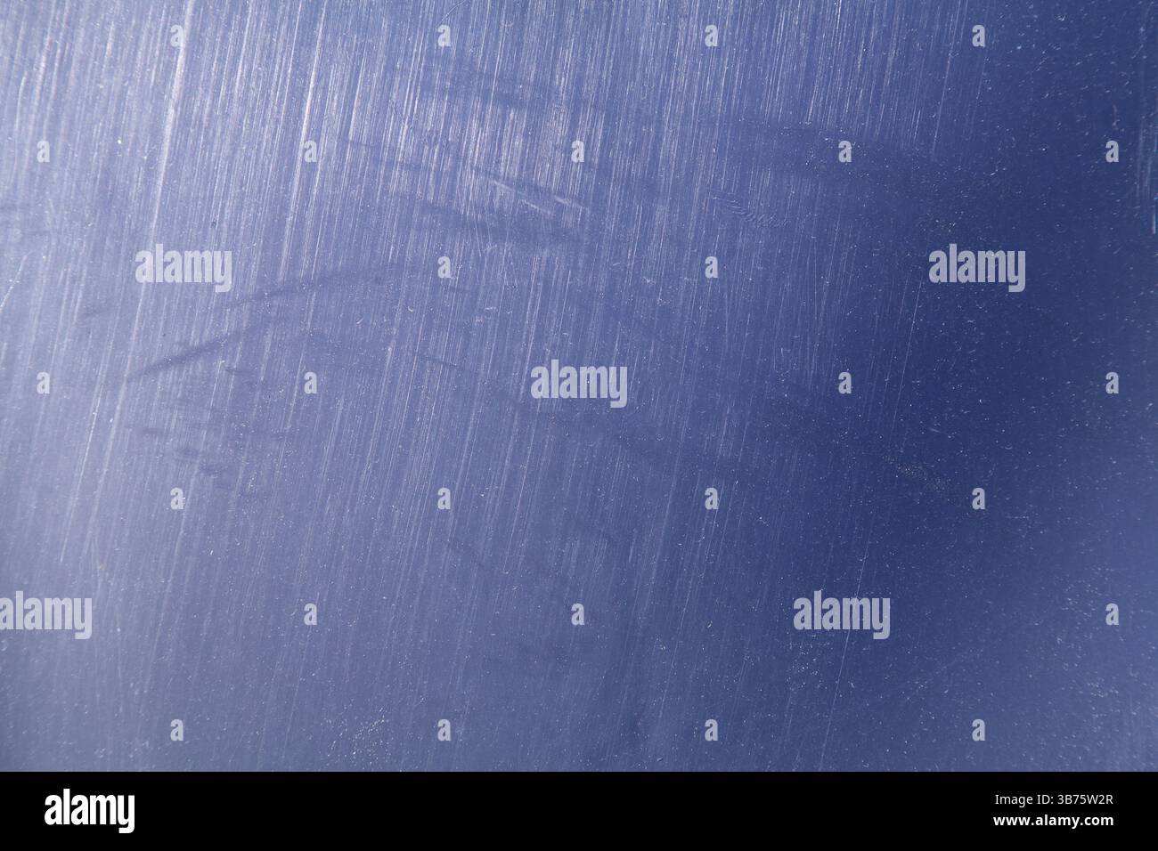 Glossy blue plastic surface with visible scratches and dust particles ...