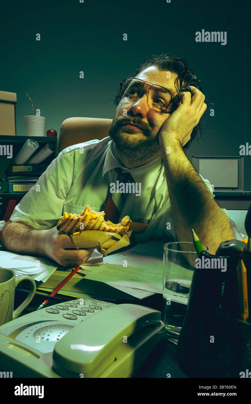 Daydreaming office worker holding sandwich, looks up with bored face at ...