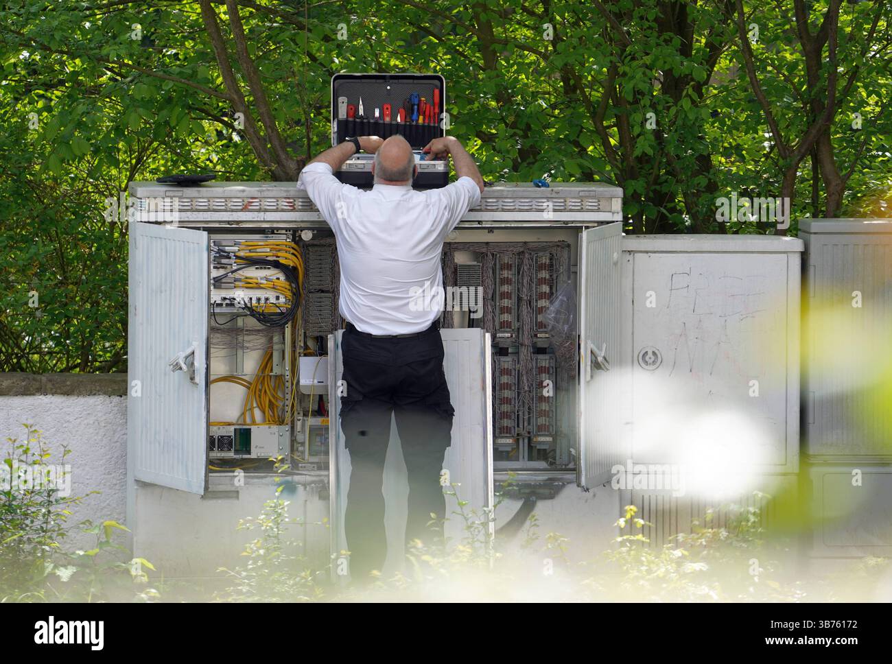 Ein Techniker der Deutschen Telekom an einem Telefonverteilerkasten in ...