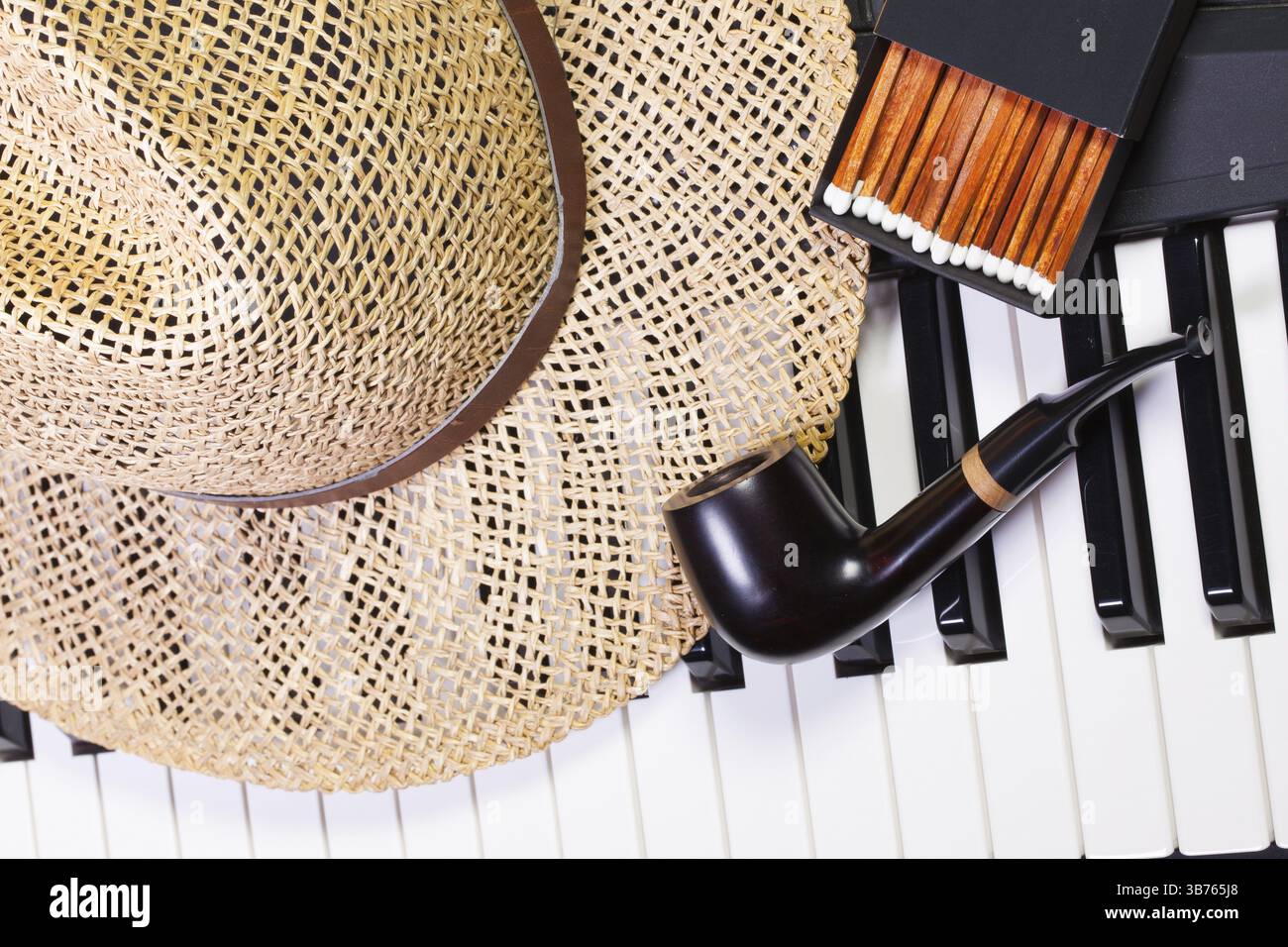 Detail of piano keyboard, straw hat and luxury pipe Stock Photo - Alamy