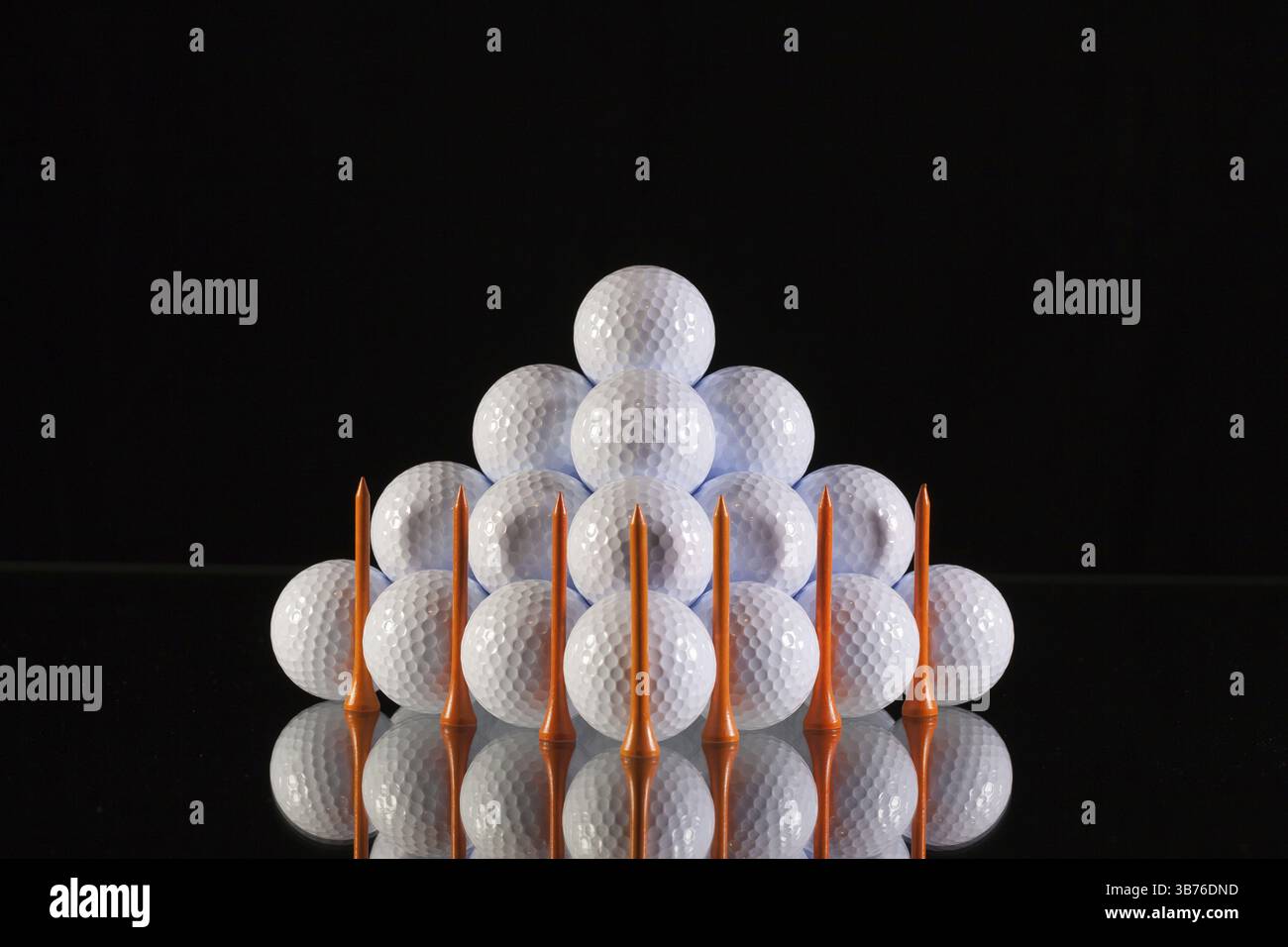 Pyramid of golf balls on a black background Stock Photo - Alamy