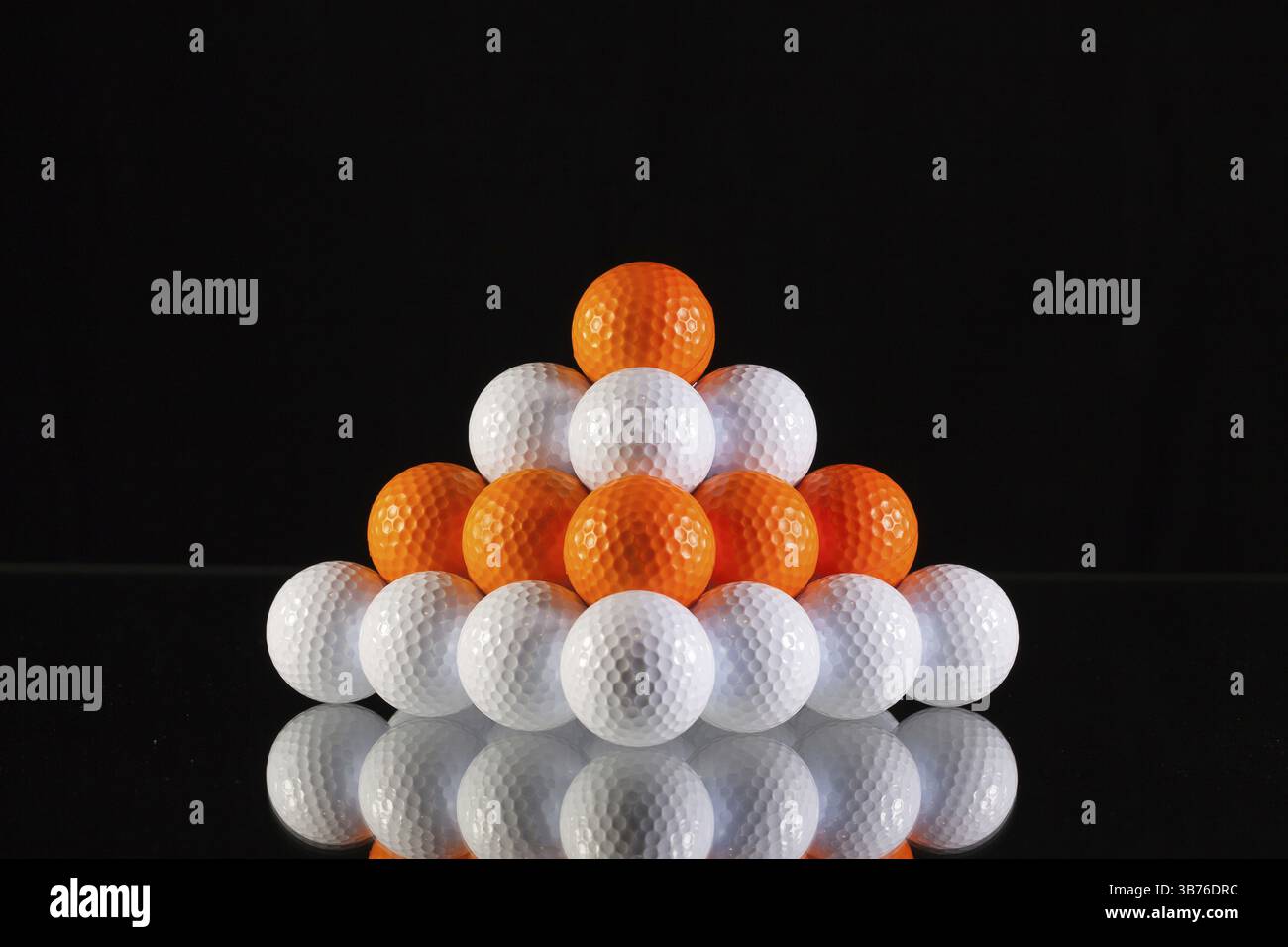 Pyramid of golf balls on a black background Stock Photo - Alamy