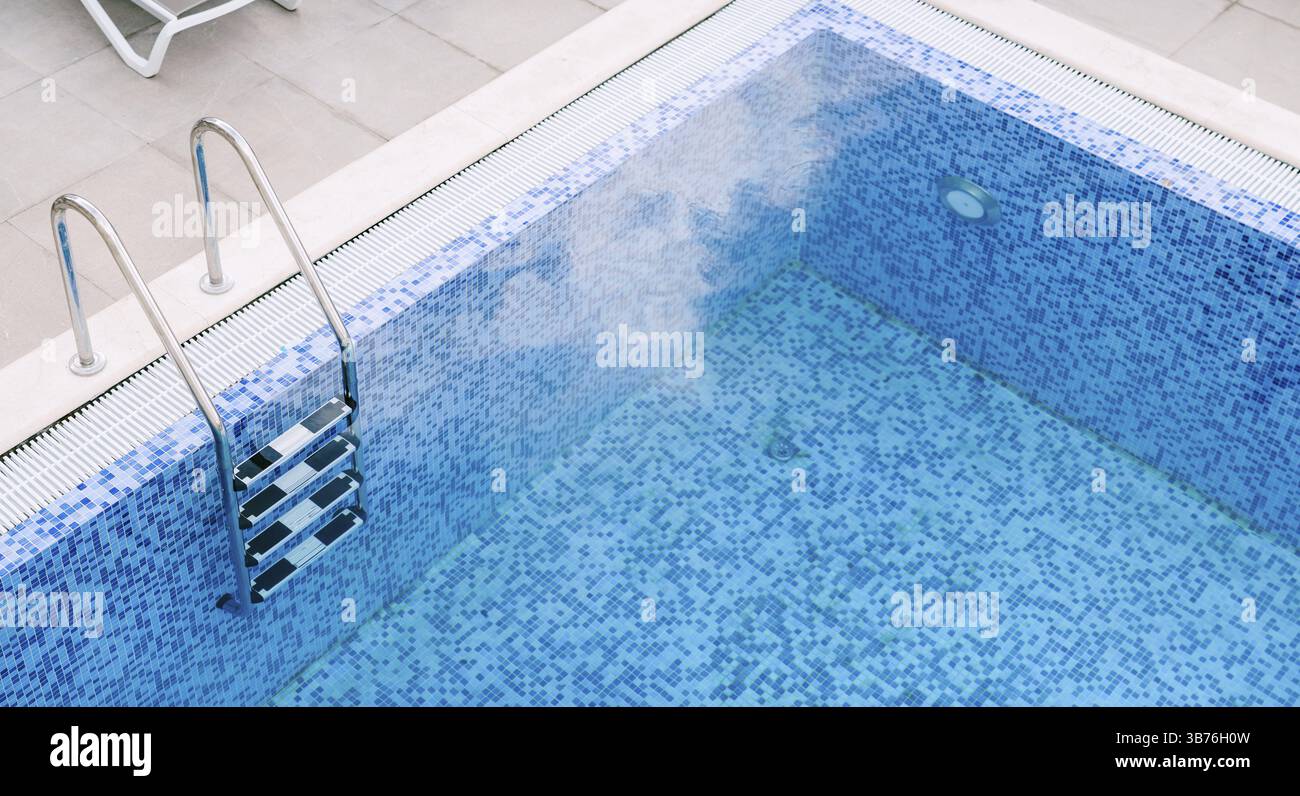 A chrome staircase with railings in a pool with blue mosaic Stock Photo ...