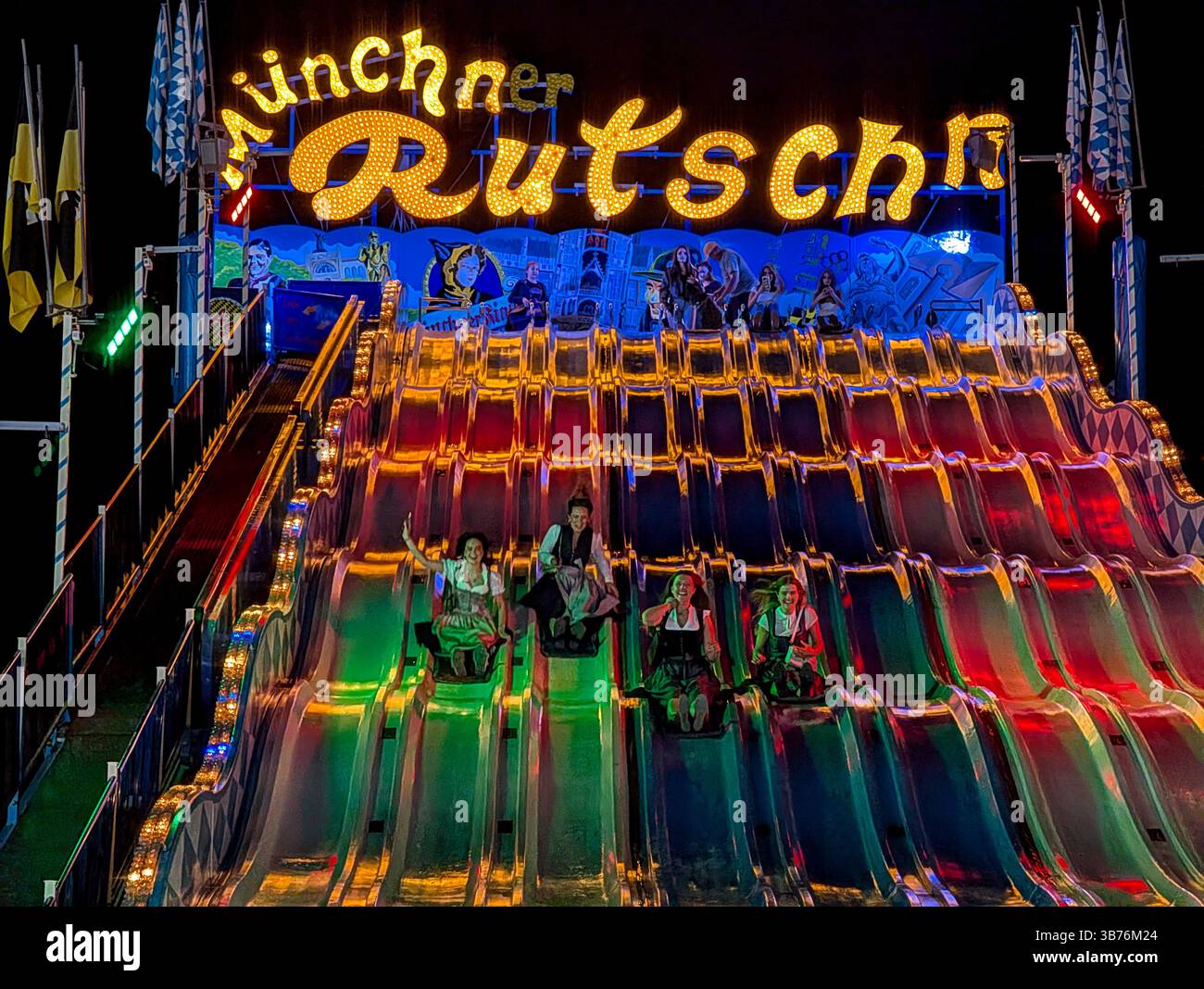 People dressed in traditional Bavarian clothing slide down the Munich ...