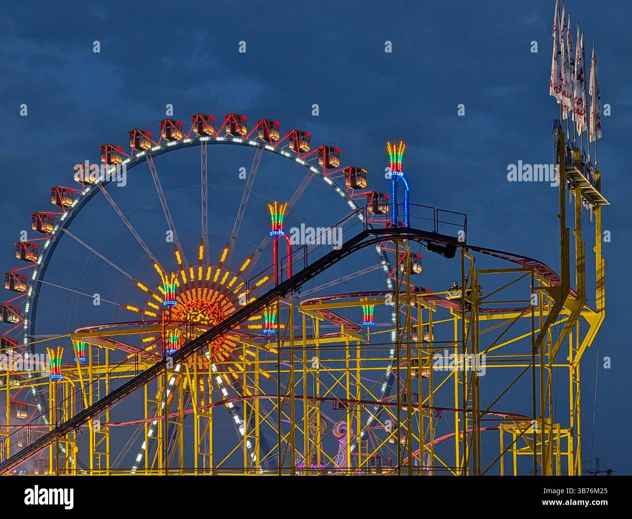 A brightly lit Ferris wheel and roller coaster are seen at night during ...
