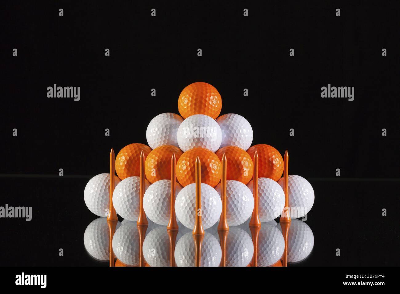 Pyramid of golf balls on a black background Stock Photo - Alamy