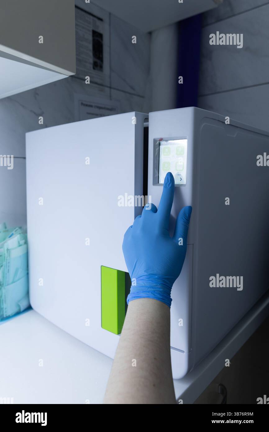 This image shows a hand wearing a blue glove pressing a button on a ...