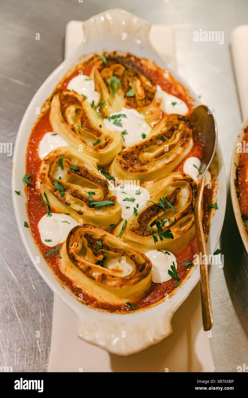 Layered pasta rolls are placed in a rustic dish, topped with tomato ...