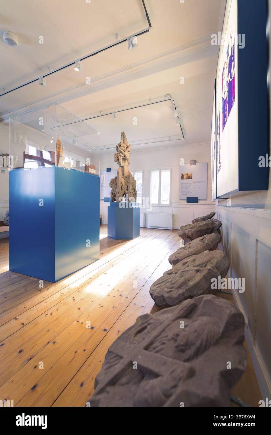Bright exhibition room with works of art on a blue plinth and wooden ...