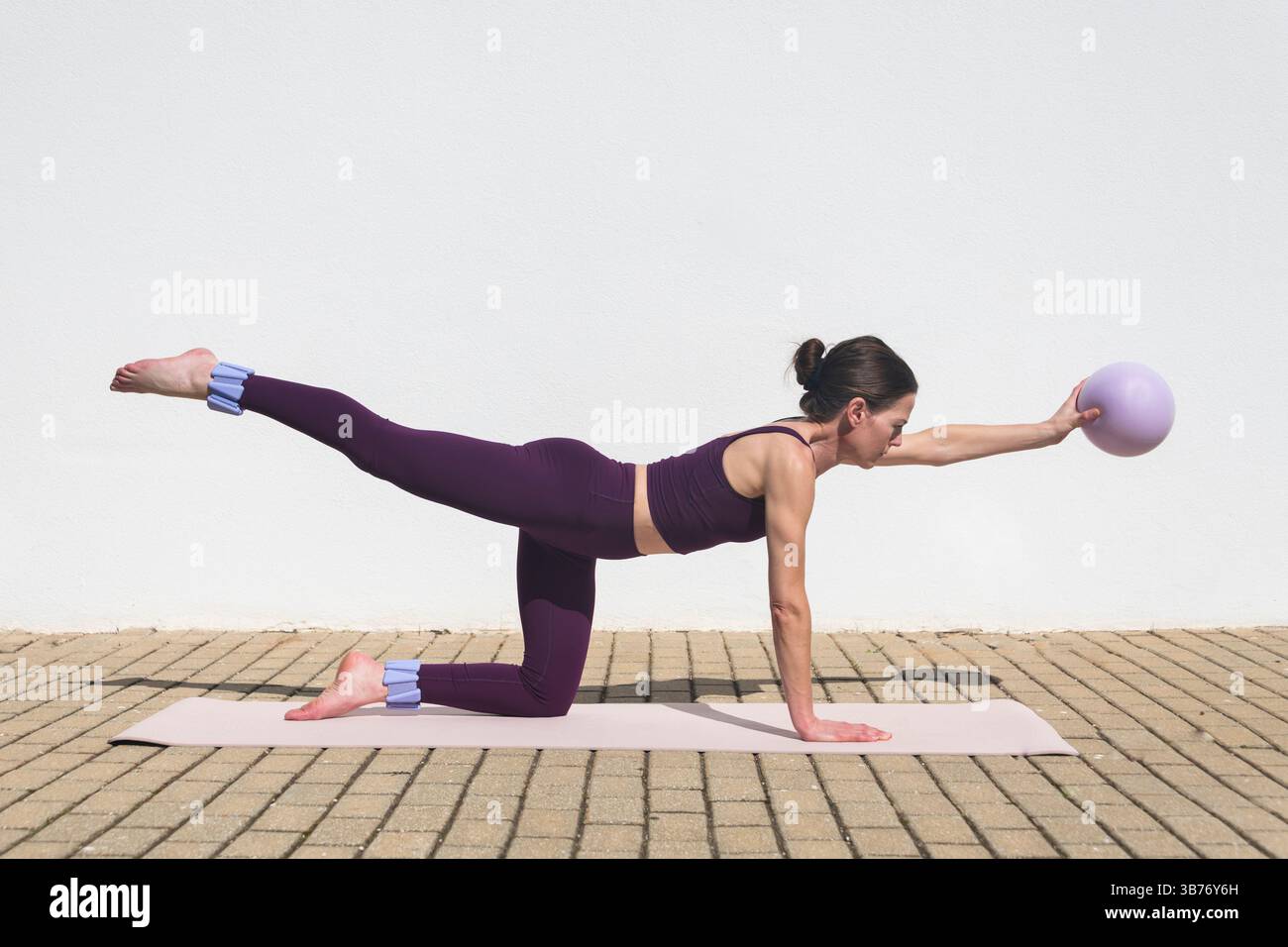 toned woman doing pilates exercise, table top pose with ball and ...
