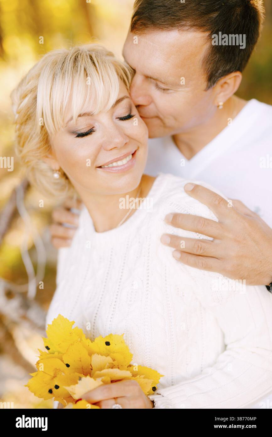 Man kisses and hugs smiling woman by the shoulders. The woman has ...