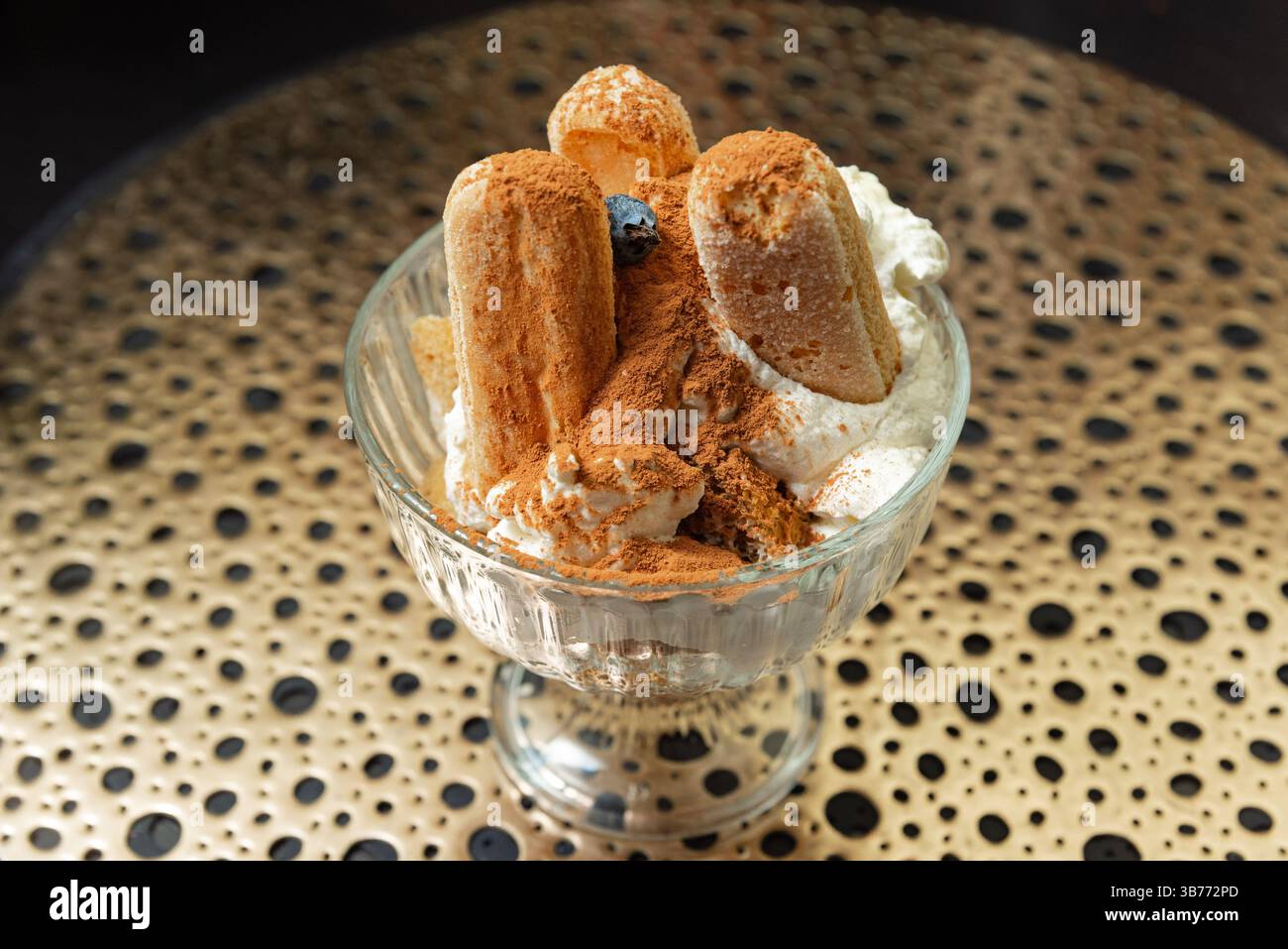 Traditional tiramisu served in a glass dessert dish with ladyfingers ...