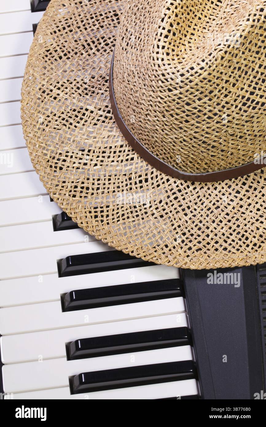 Detail of piano keyboard and straw hat Stock Photo - Alamy