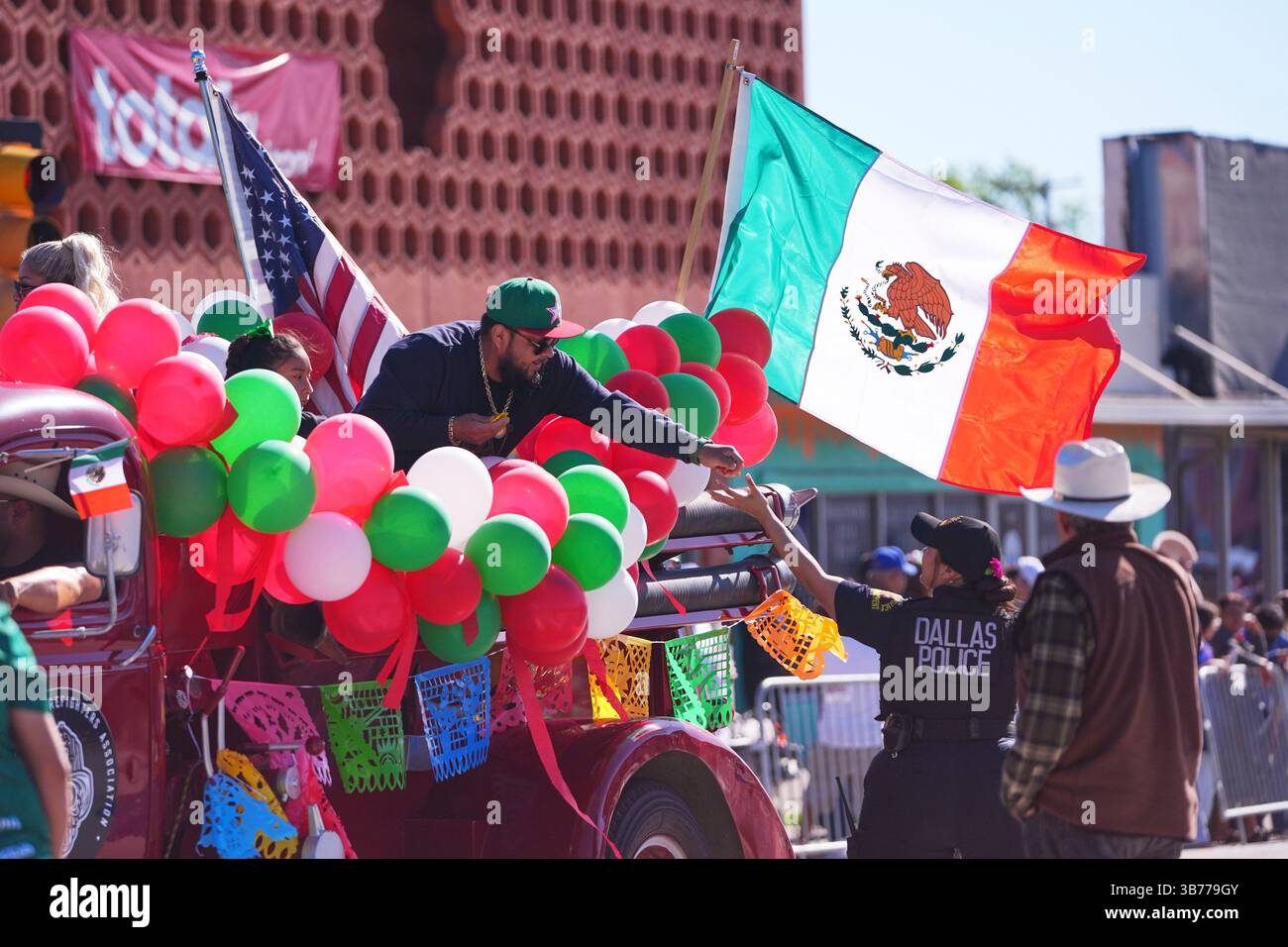 A float rider hands candy to a Dallas police officer during a Cinco de ...