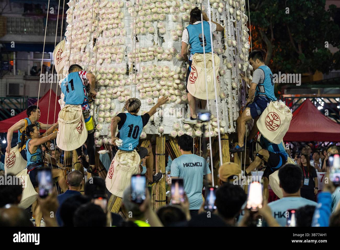 Participants collect buns from a tower covered with plastic buns during ...