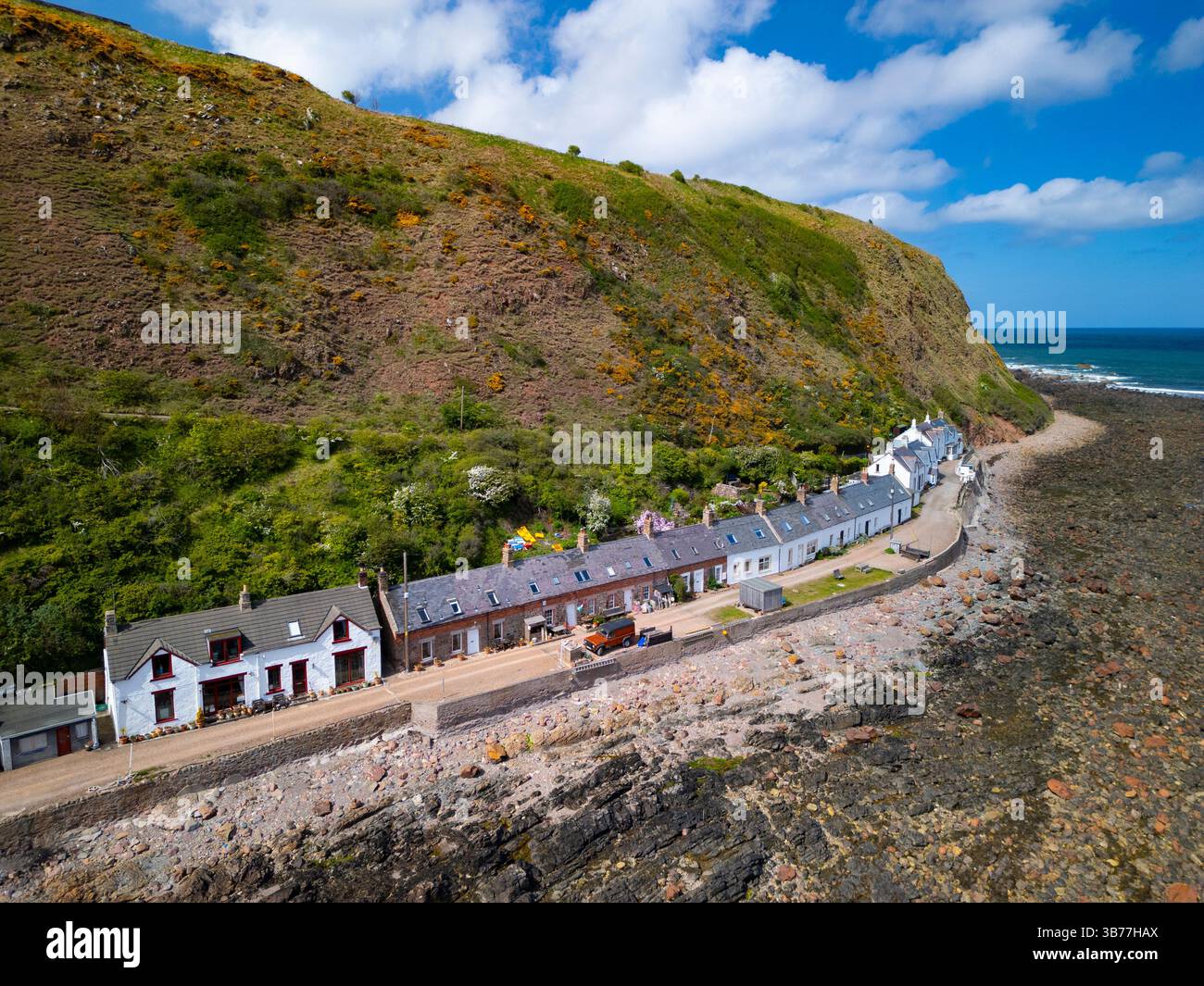 Aerial view of row of houses at base of cliffs in village of Burnmouth ...