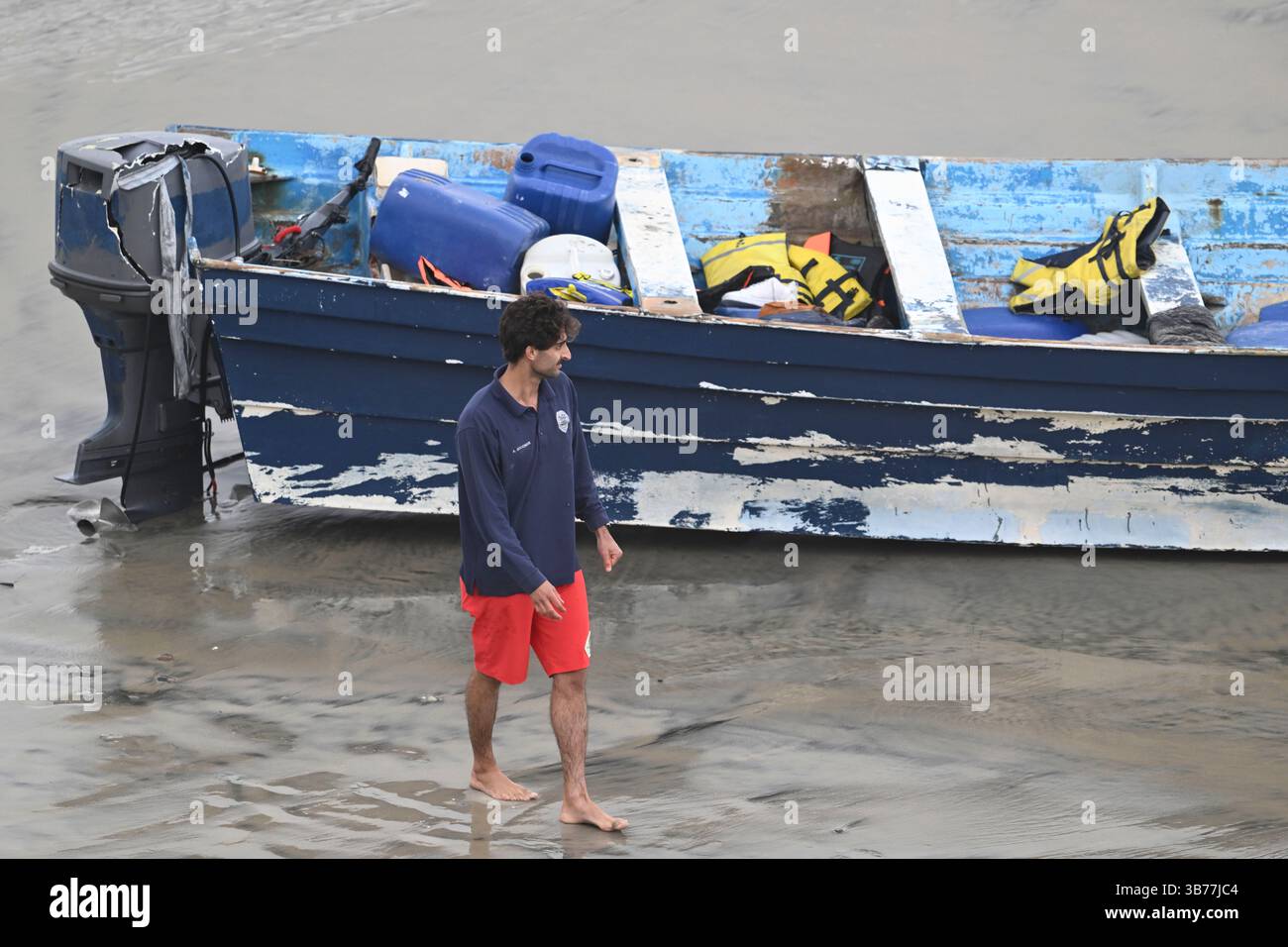 CORRECTS DAY A Del Mar lifeguard looks over a capsized boat on the ...