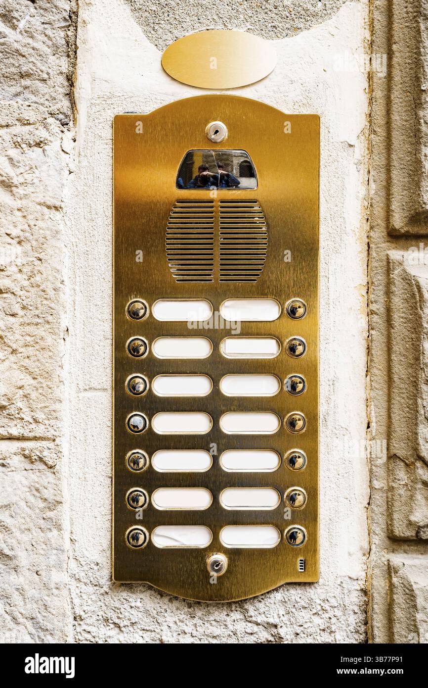 The intercom is golden, metal with buttons and blank columns for ...