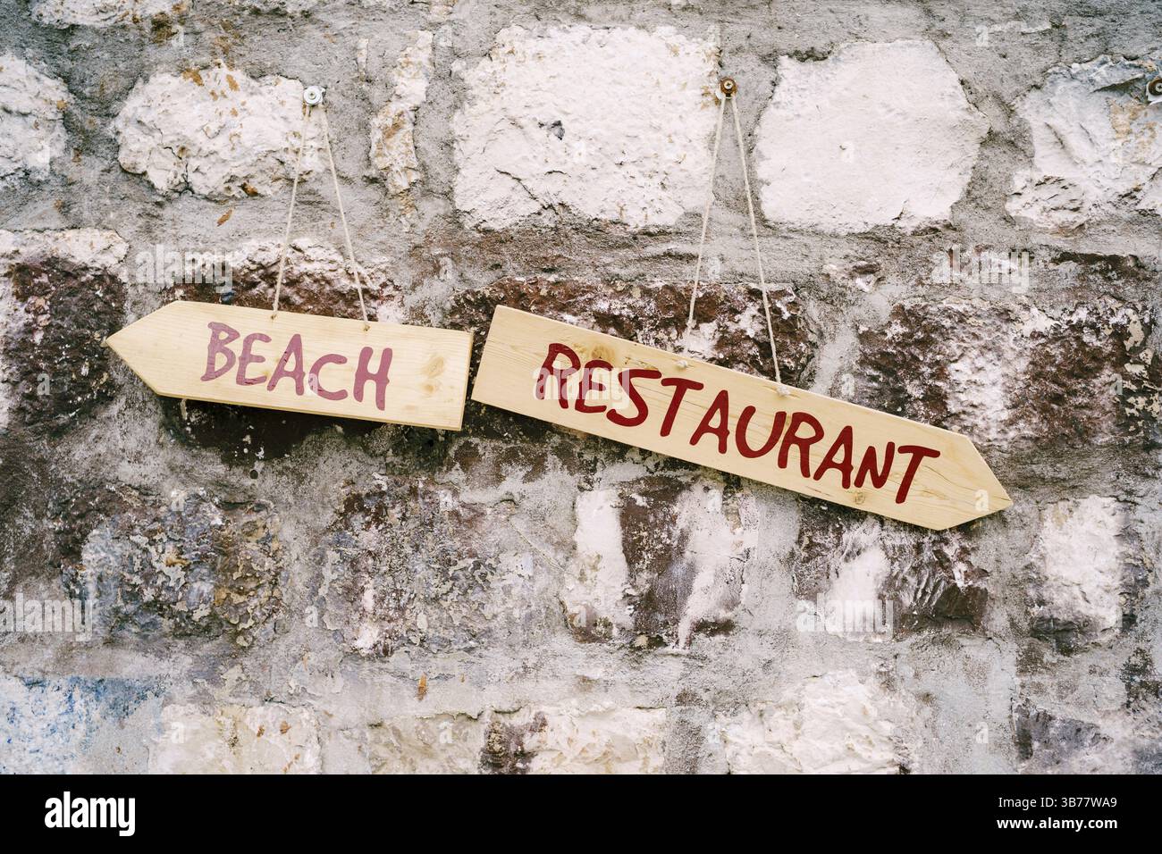 Two multidirectional signs with inscriptions hang on a stone wall Stock ...