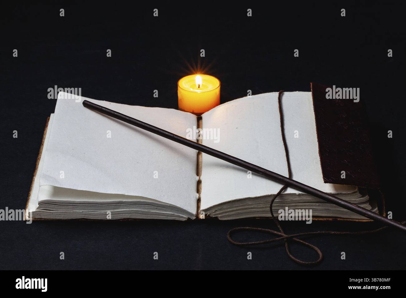 Image of open magic book, wand and burning candle on the table in the ...