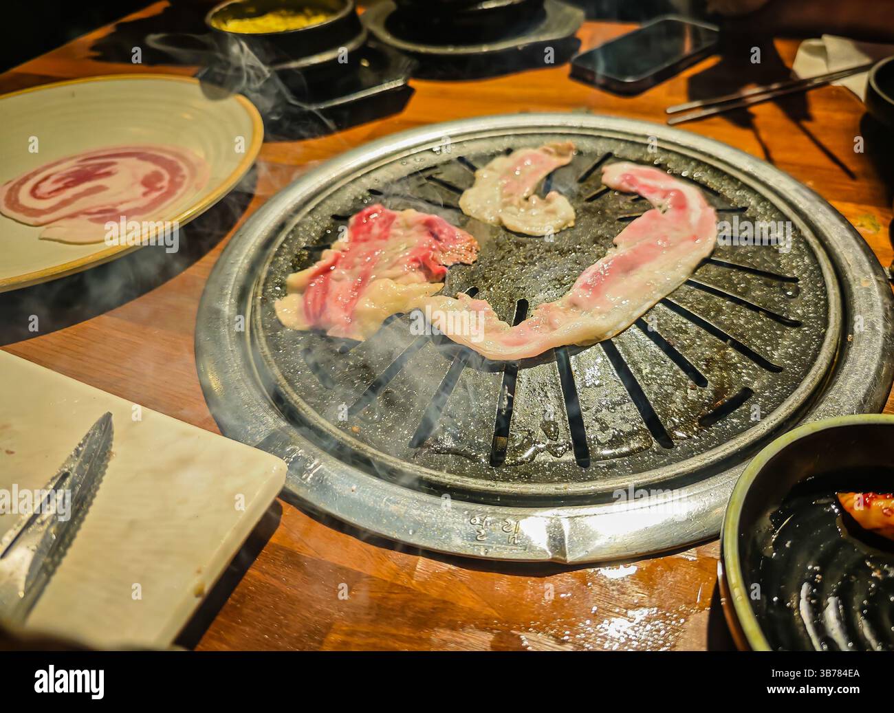 Korean BBQ style restaurant. Traditional Korea dining table with grill inside. Pork belly and ...