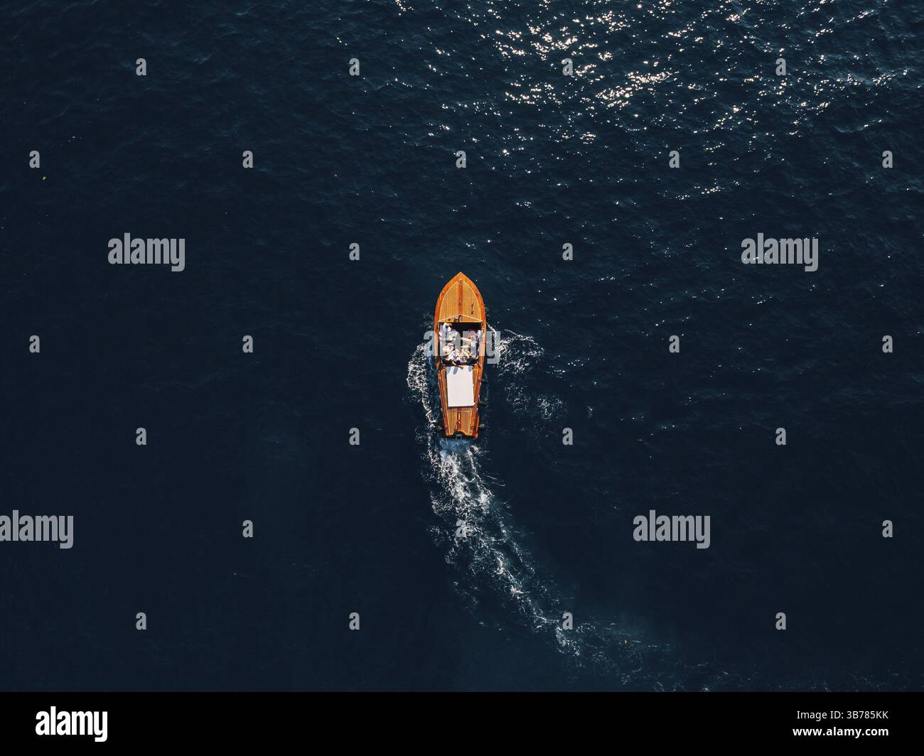A wooden sports boat with people on board rides on the sea. Luxury ...