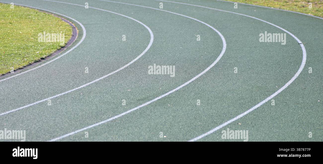 Green running track curve with white lines and green grass in the sides ...