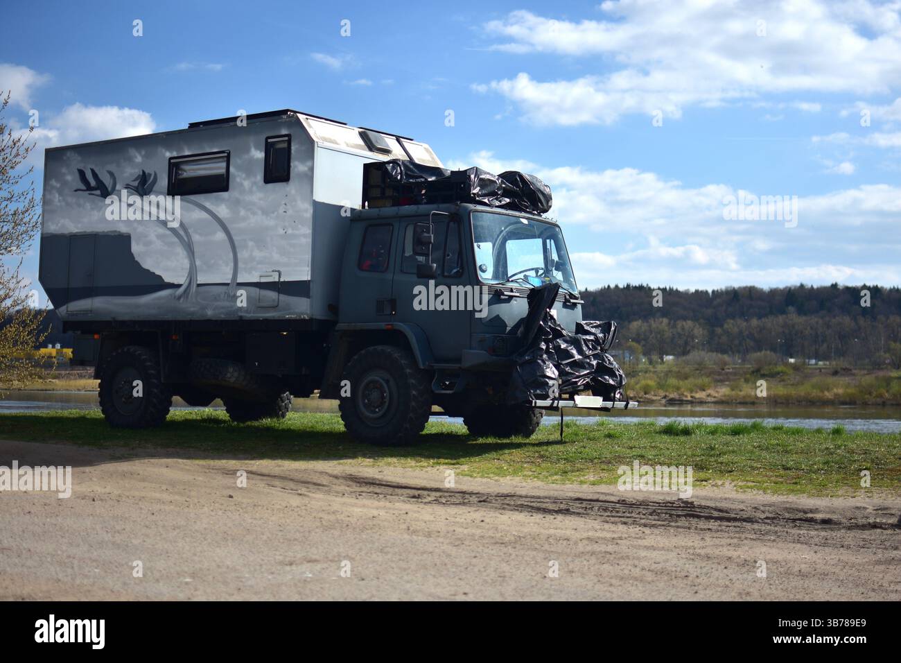 Heavy loaded camper truck standing near river side. Travel expedition ...