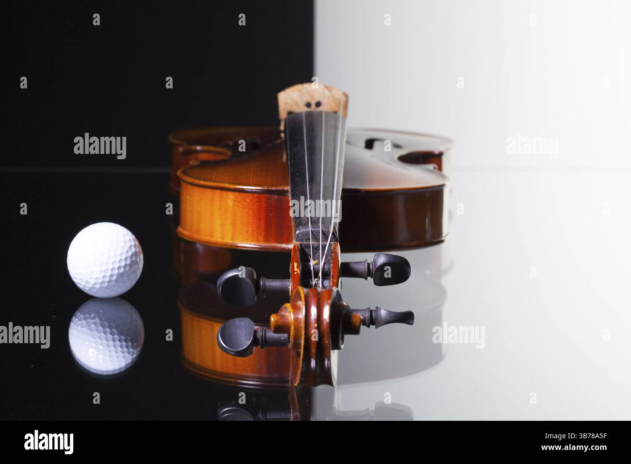 Old violin and golf ball isolated on black and white background and ...