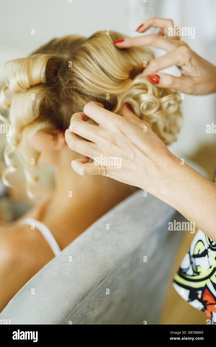 The stylist fixes the styling for a woman with long blond hair using ...