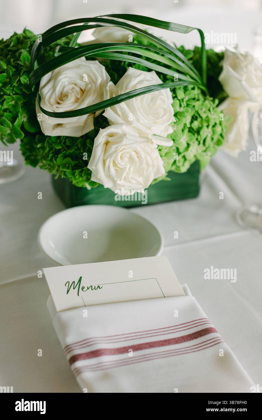 A beautifully arranged table displays white roses and hydrangeas with a ...
