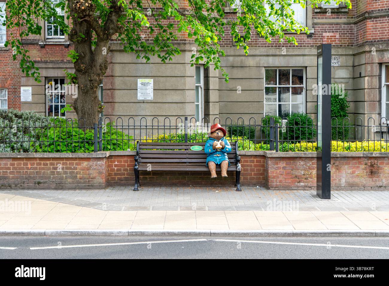 Statue of Paddington Bear sitting on a bench seat eating a marmalade ...