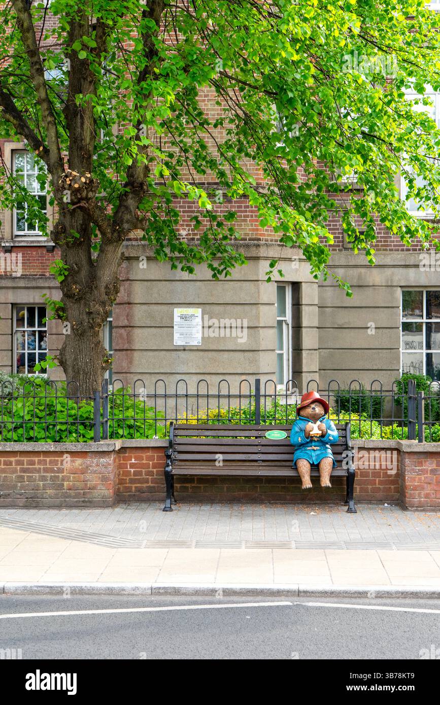 Statue of Paddington Bear sitting on a bench seat eating a marmalade ...