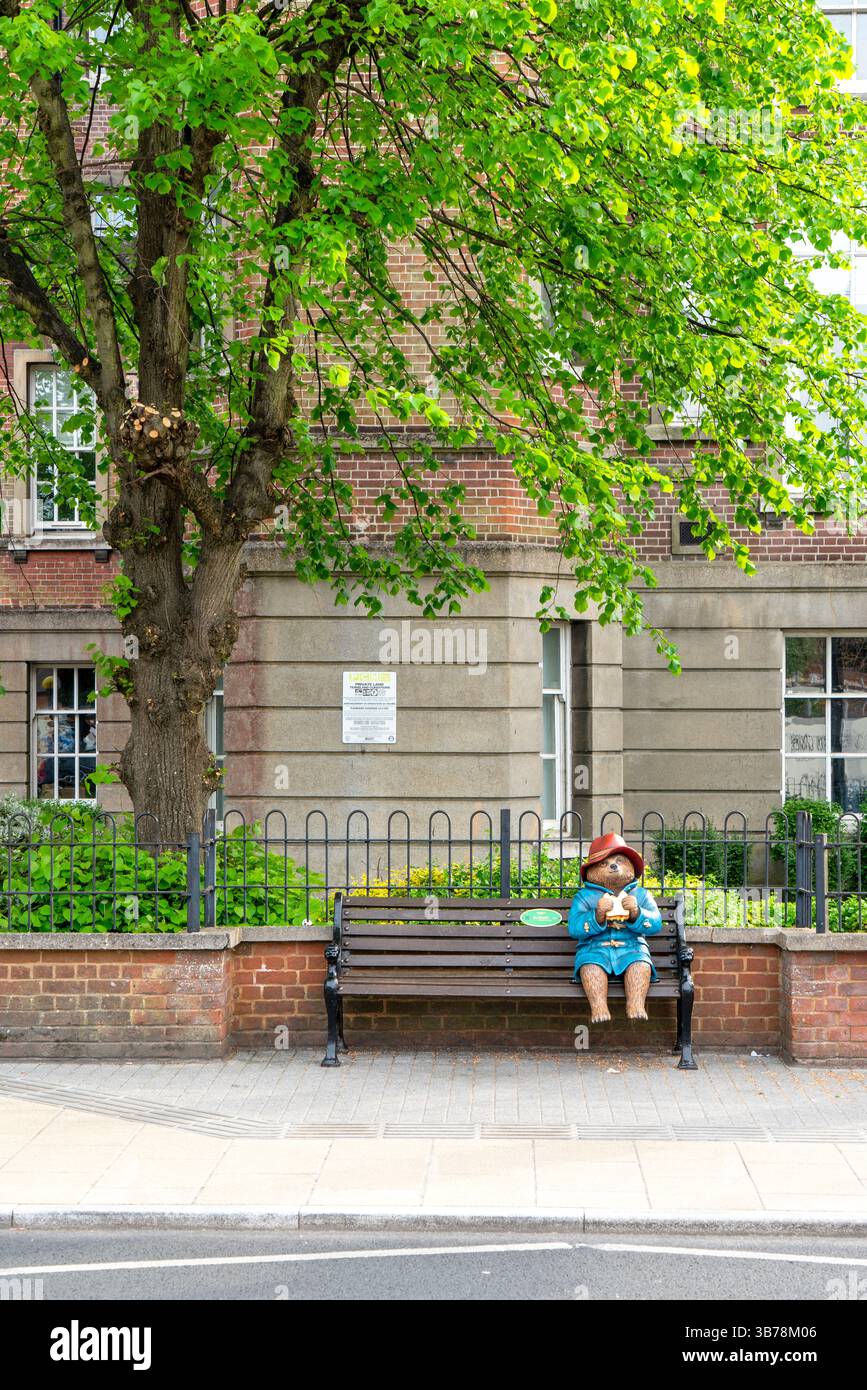 Statue of Paddington Bear sitting on a bench seat eating a marmalade ...
