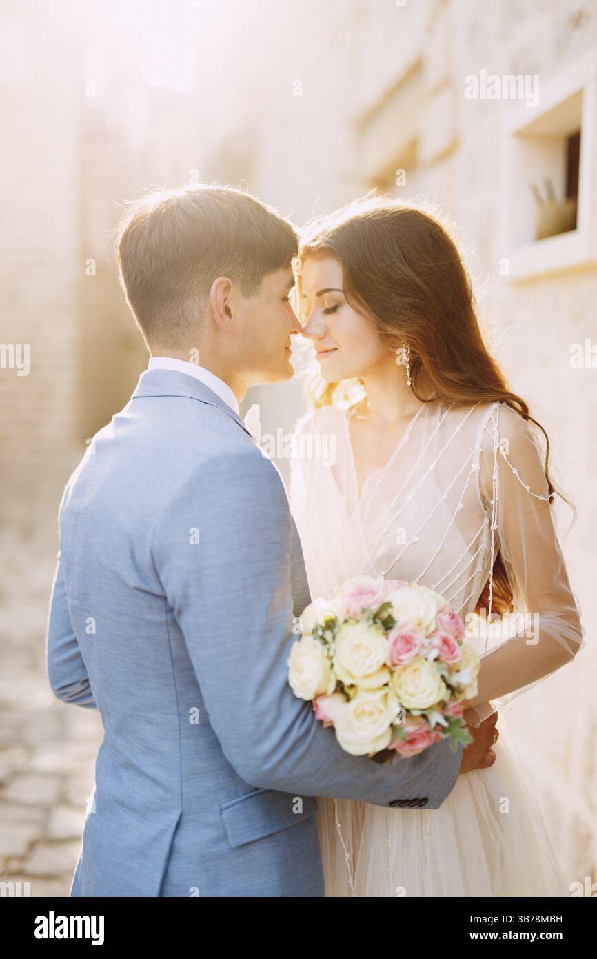 The bride and groom hug on a beautiful old street of Perast near a ...