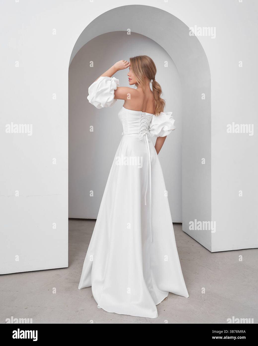 Blonde woman in elegant wedding dress poses gracefully in bright ...