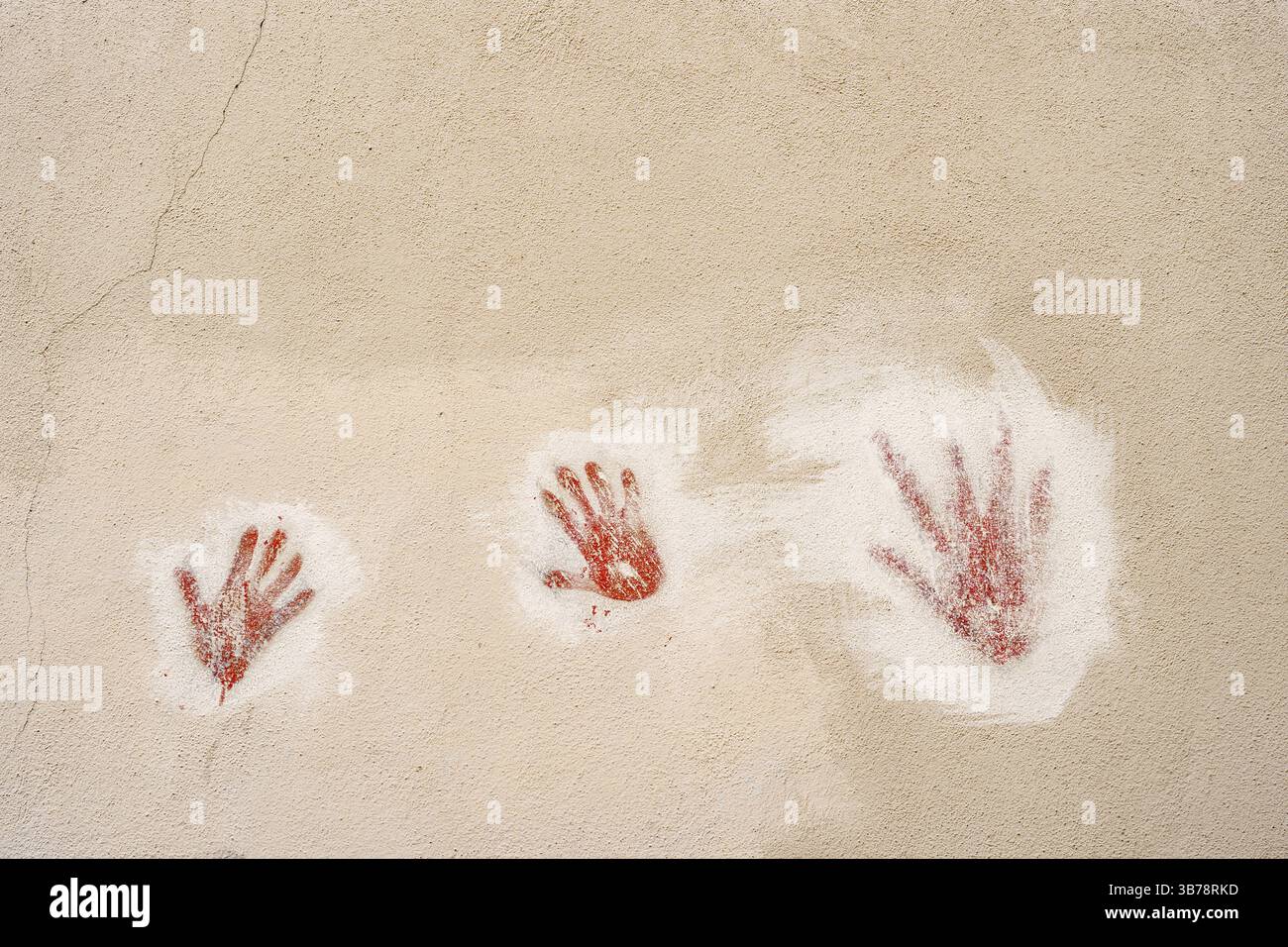 Red handprints on the wall. Two children's handprints and one adult ...