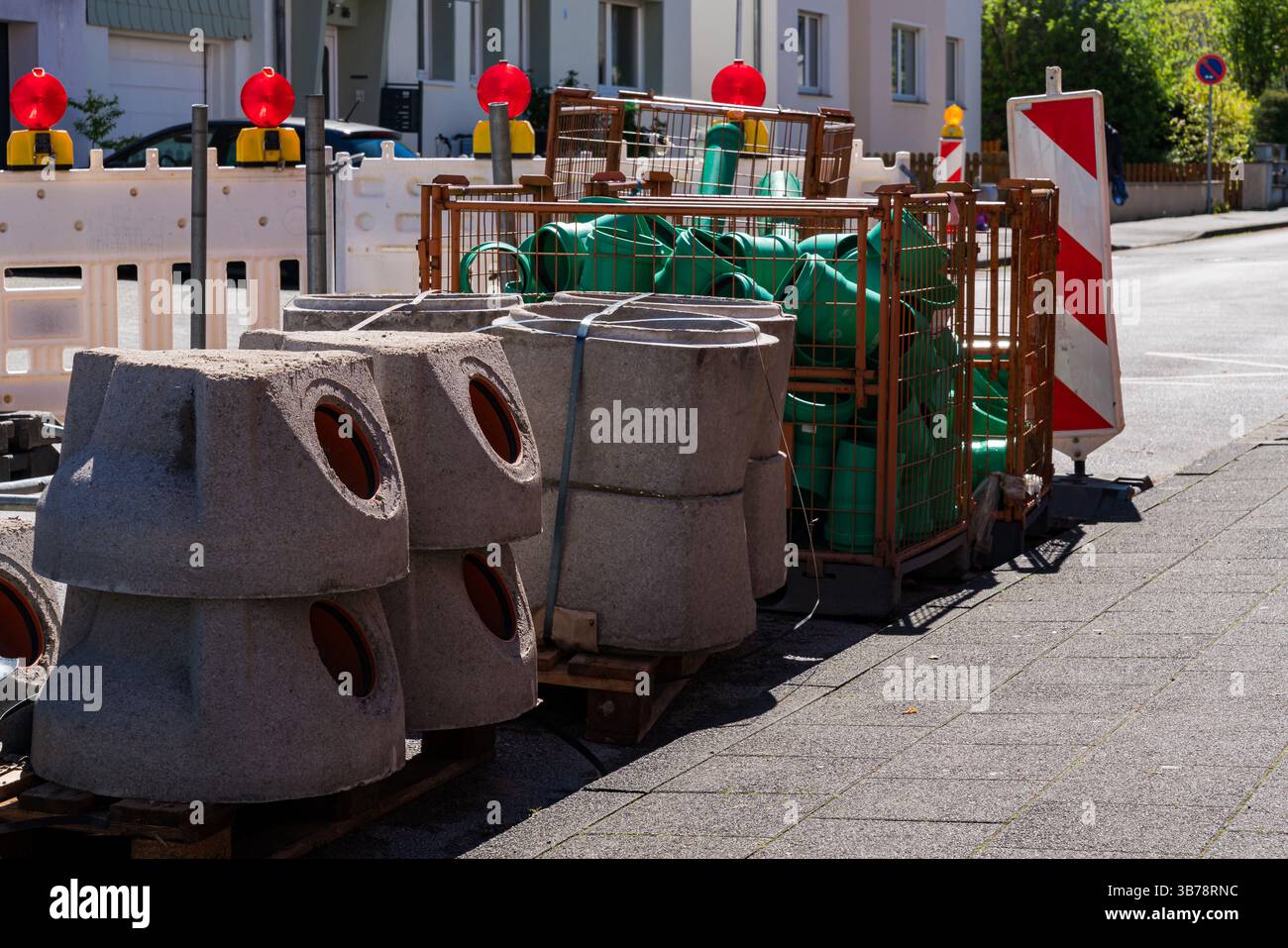 Concrete pipes, safety barriers, and construction materials line a city ...
