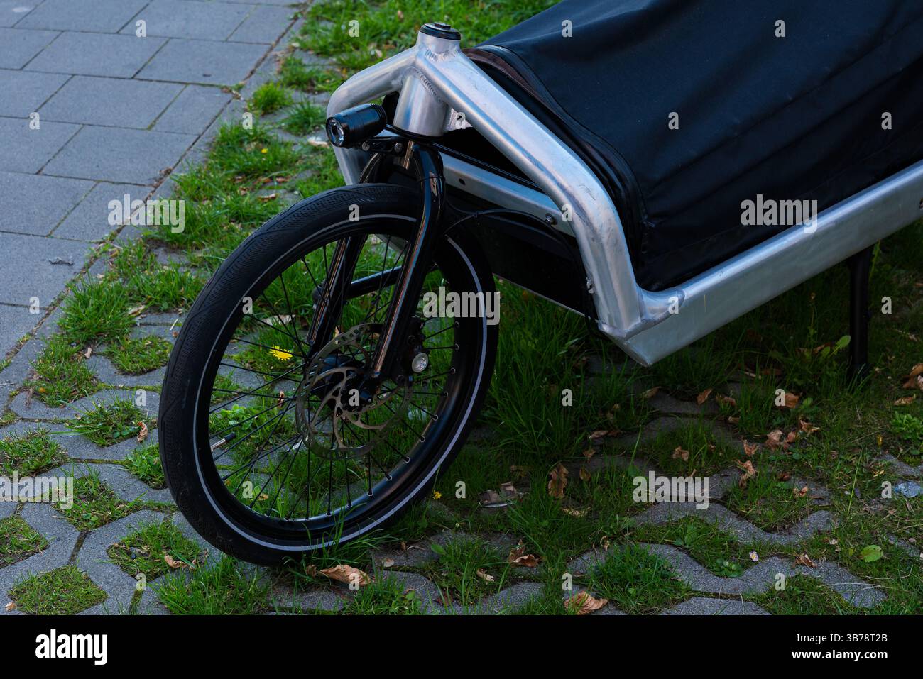 A modern bike trailer rests on a paved path, featuring a minimalist ...