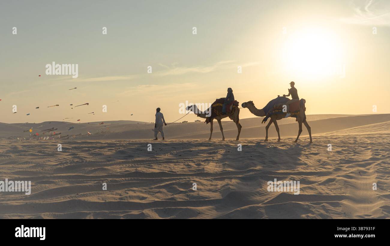 Doha, Qatar, February 24, 2025: A group of people riding camels through ...