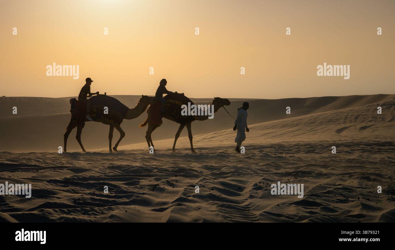 Doha, Qatar, February 24, 2025: A group of people riding camels through ...